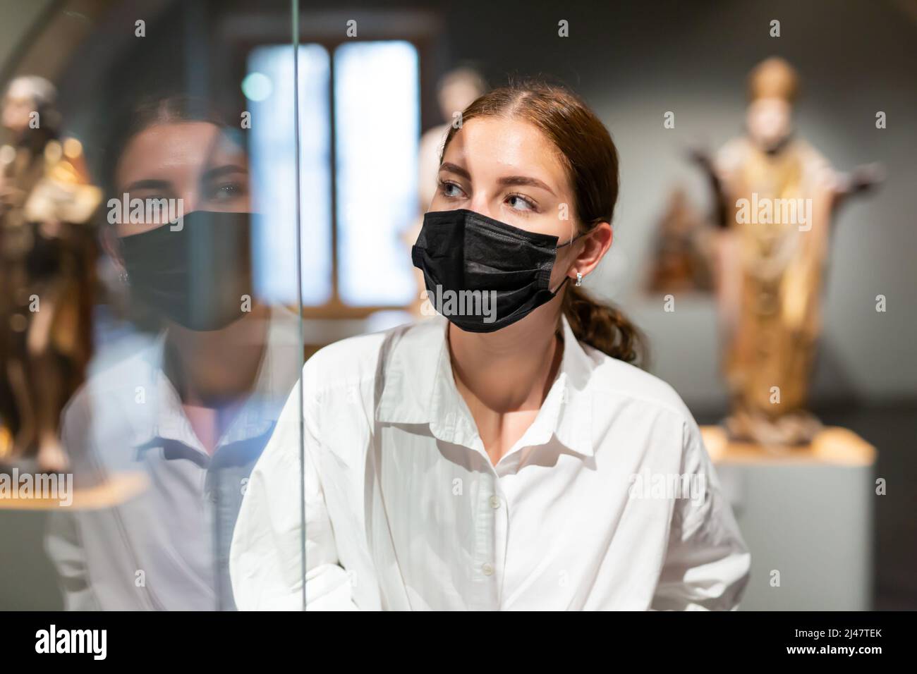 Woman in mask visiting exhibit at sculpture hall in museum Stock Photo ...
