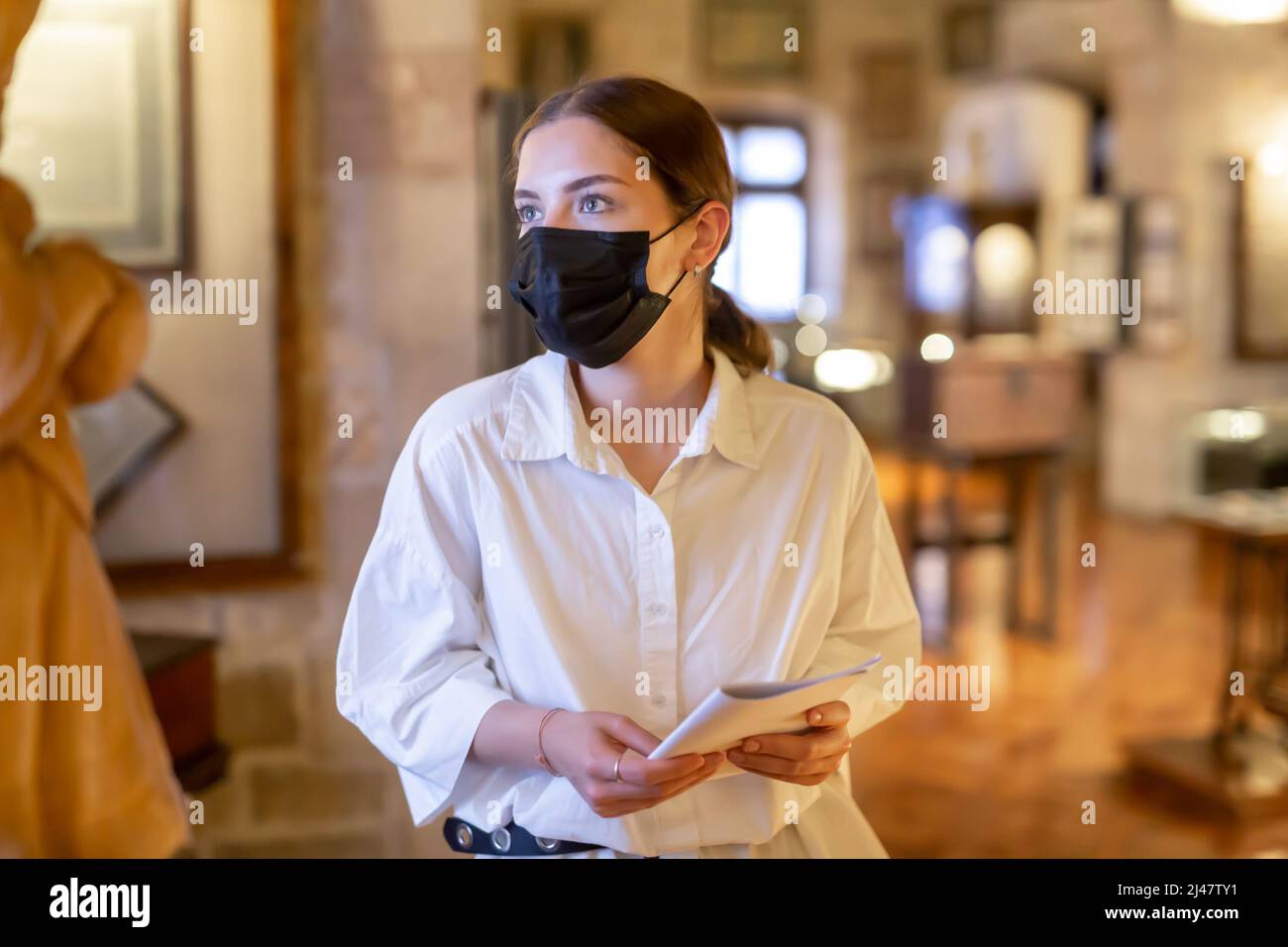 Woman in mask visiting exhibit at sculpture hall in museum Stock Photo ...