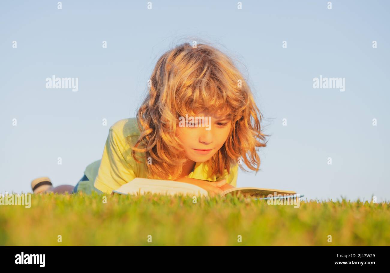 Kid read book in park. Child boy reading book laying on grass on grass ...