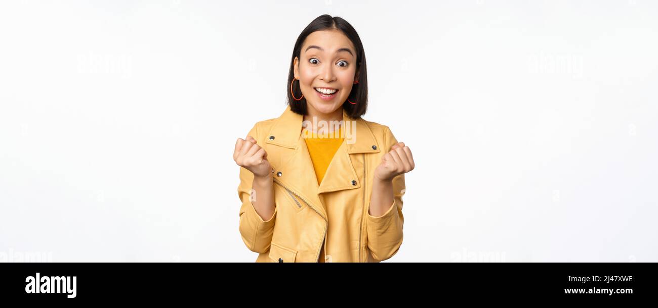 Surprised and happy asian girl, looking with happy face of rejoice ...