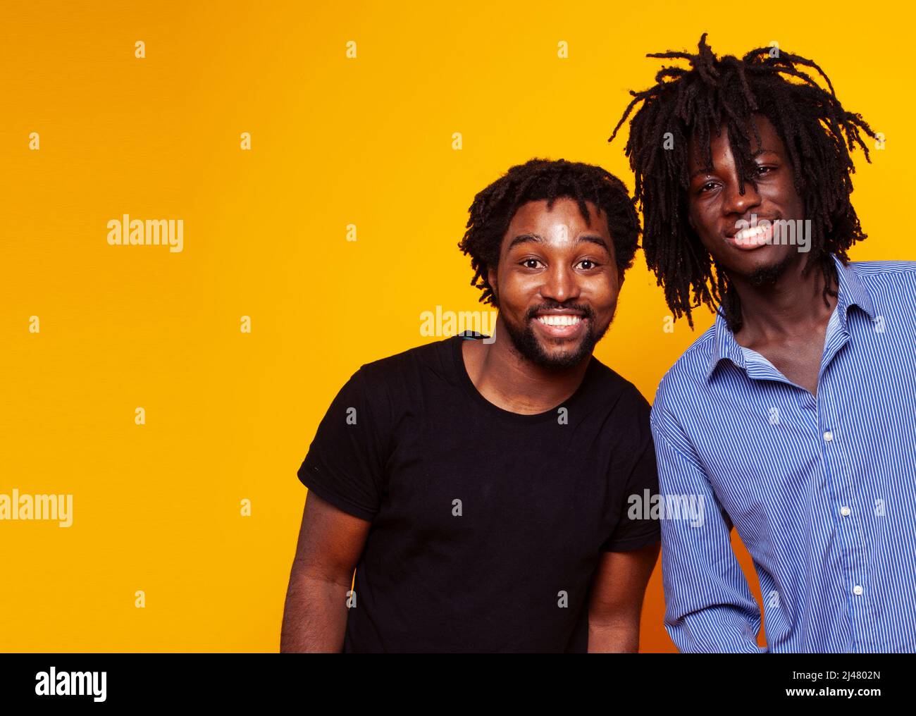 two african american guys posing cheerful together on yellow background ...
