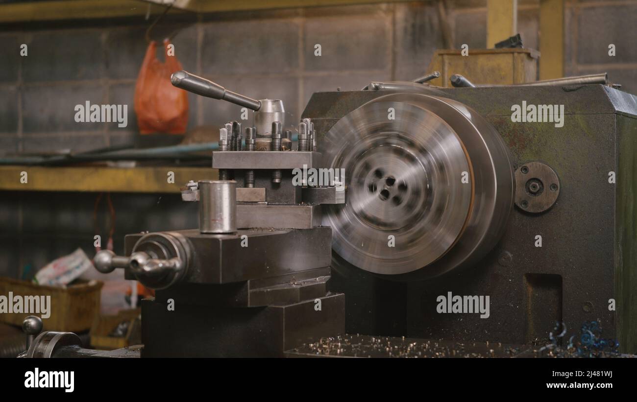Professional machinist operating lathe grinding metal machine ...