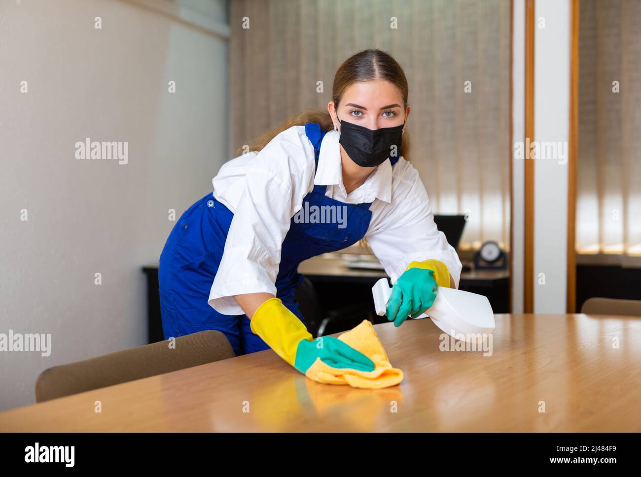 Woman in mask wiping dust from desk Stock Photo - Alamy