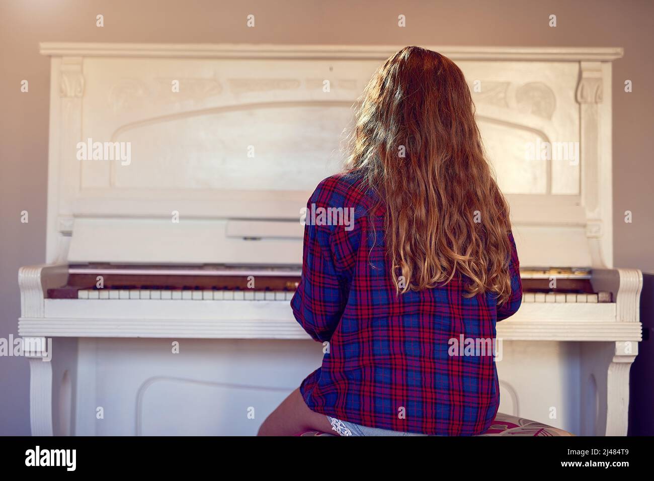 Practising her piano lesson. Rear view shot of a young girl playing the piano Stock Photo - Alamy
