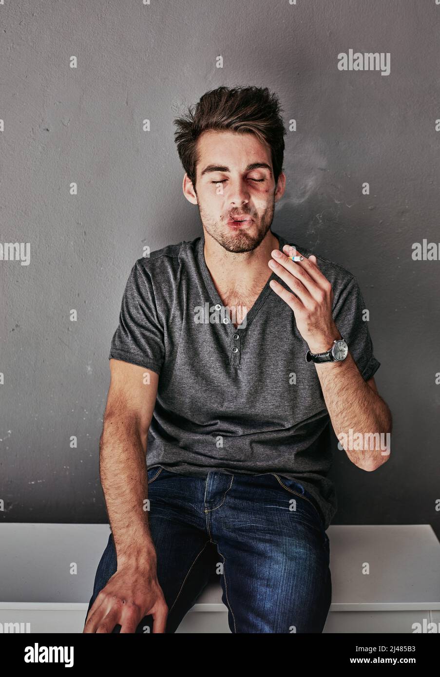 Puffing the pain away. Cropped shot of a beaten and bruised young man ...