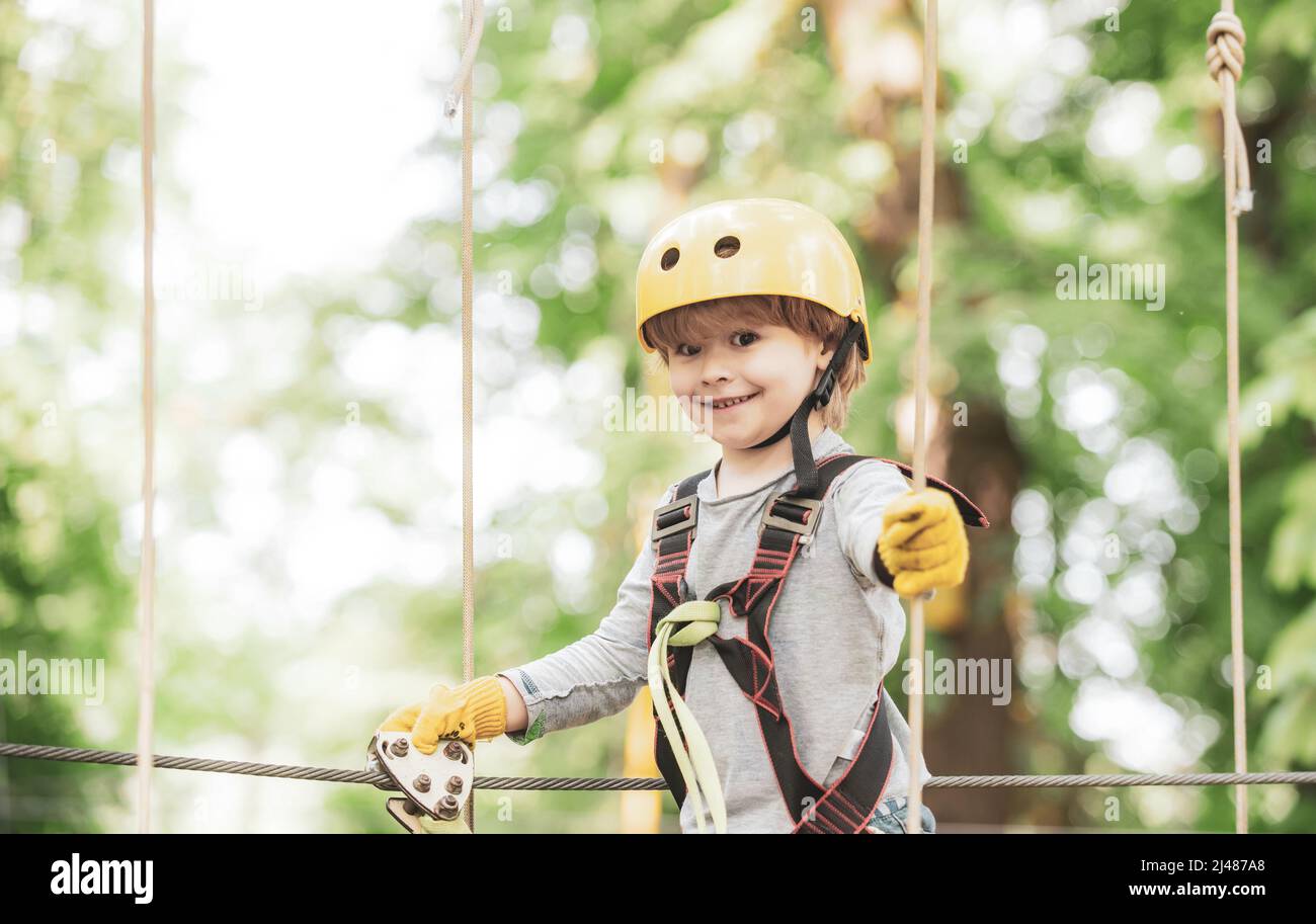 Happy child boy calling while climbing high tree and ropes. Portrait of ...