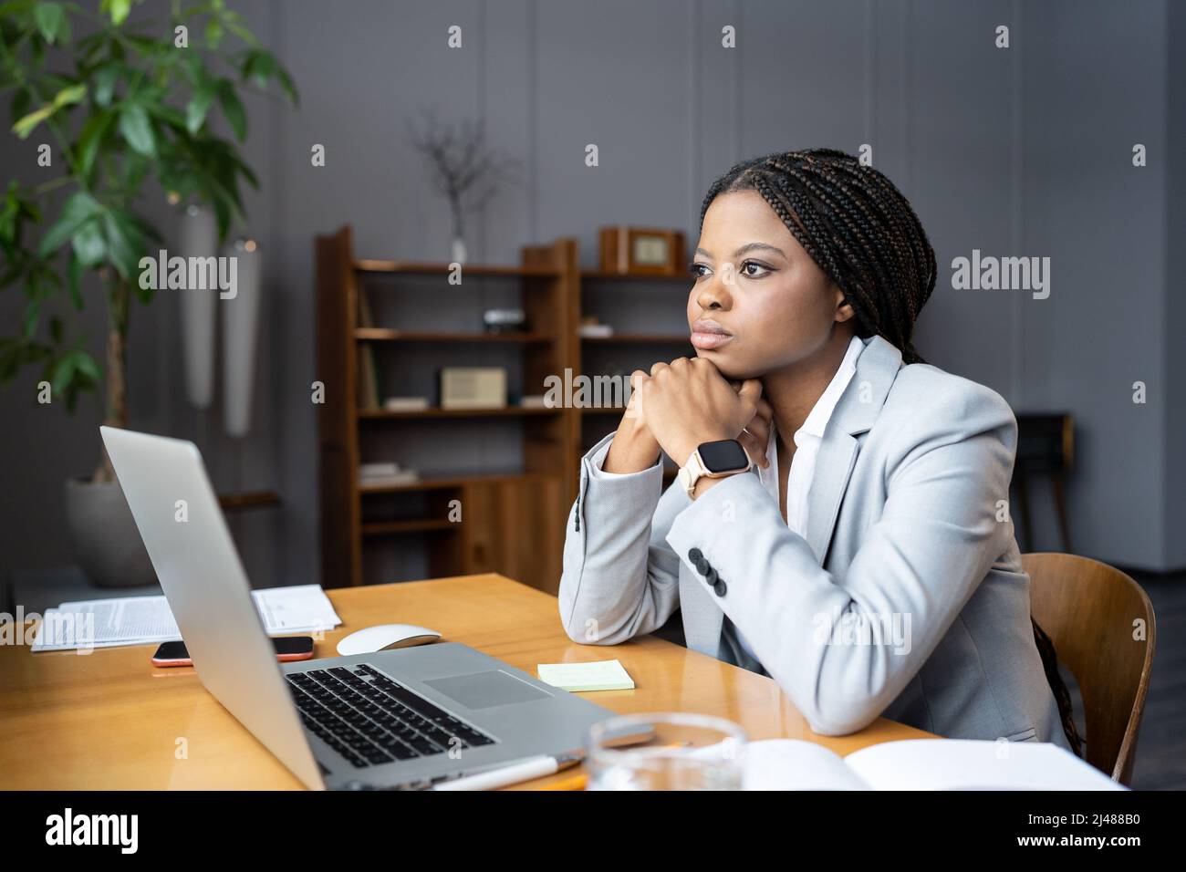 Young thoughtful african female employee looking out window at ...
