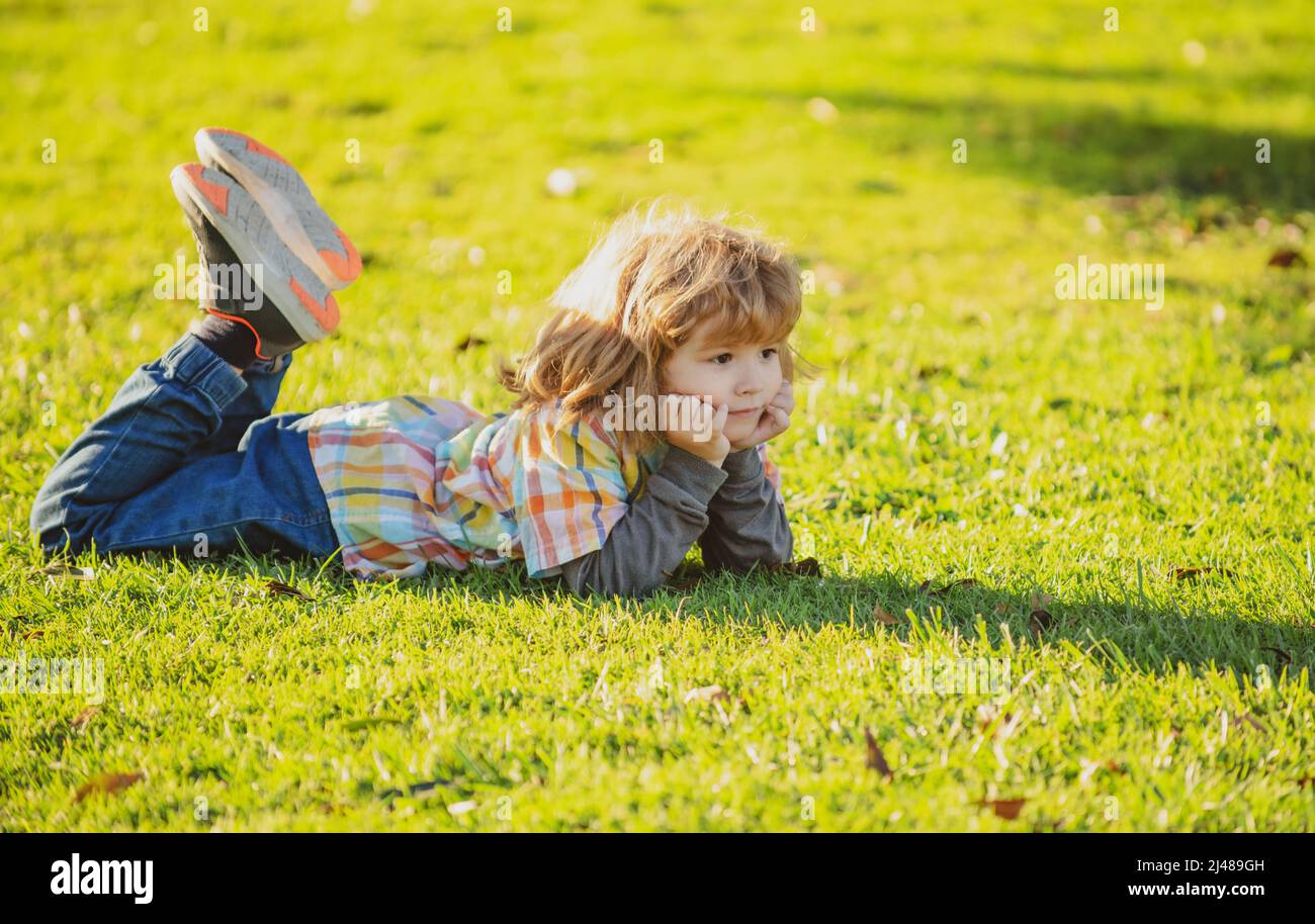 Child outdoor in park. Spring kid lying on grass. Summer boy walk ...