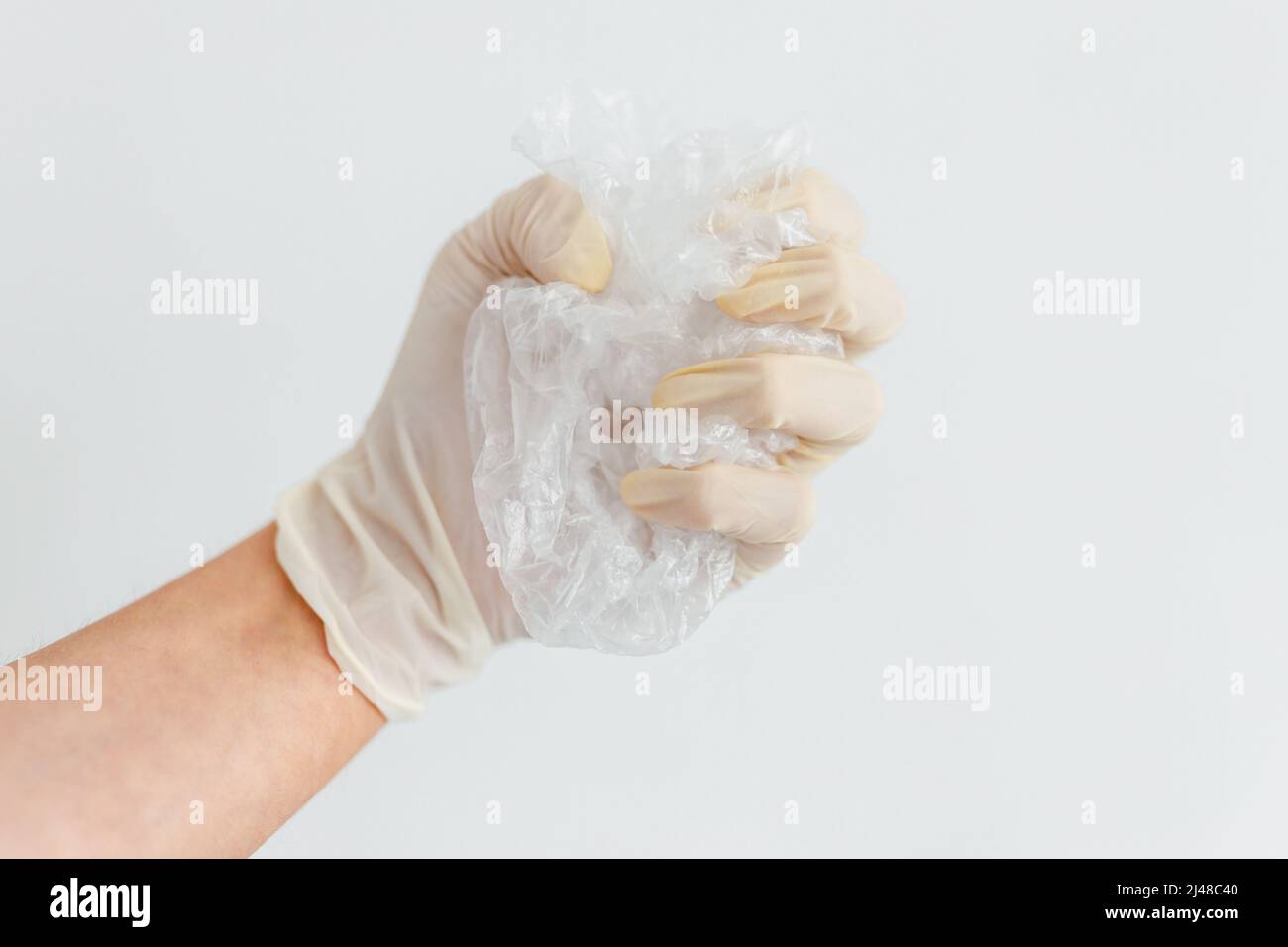 hand with glove picking up single-use plastic bag to be recycled ...