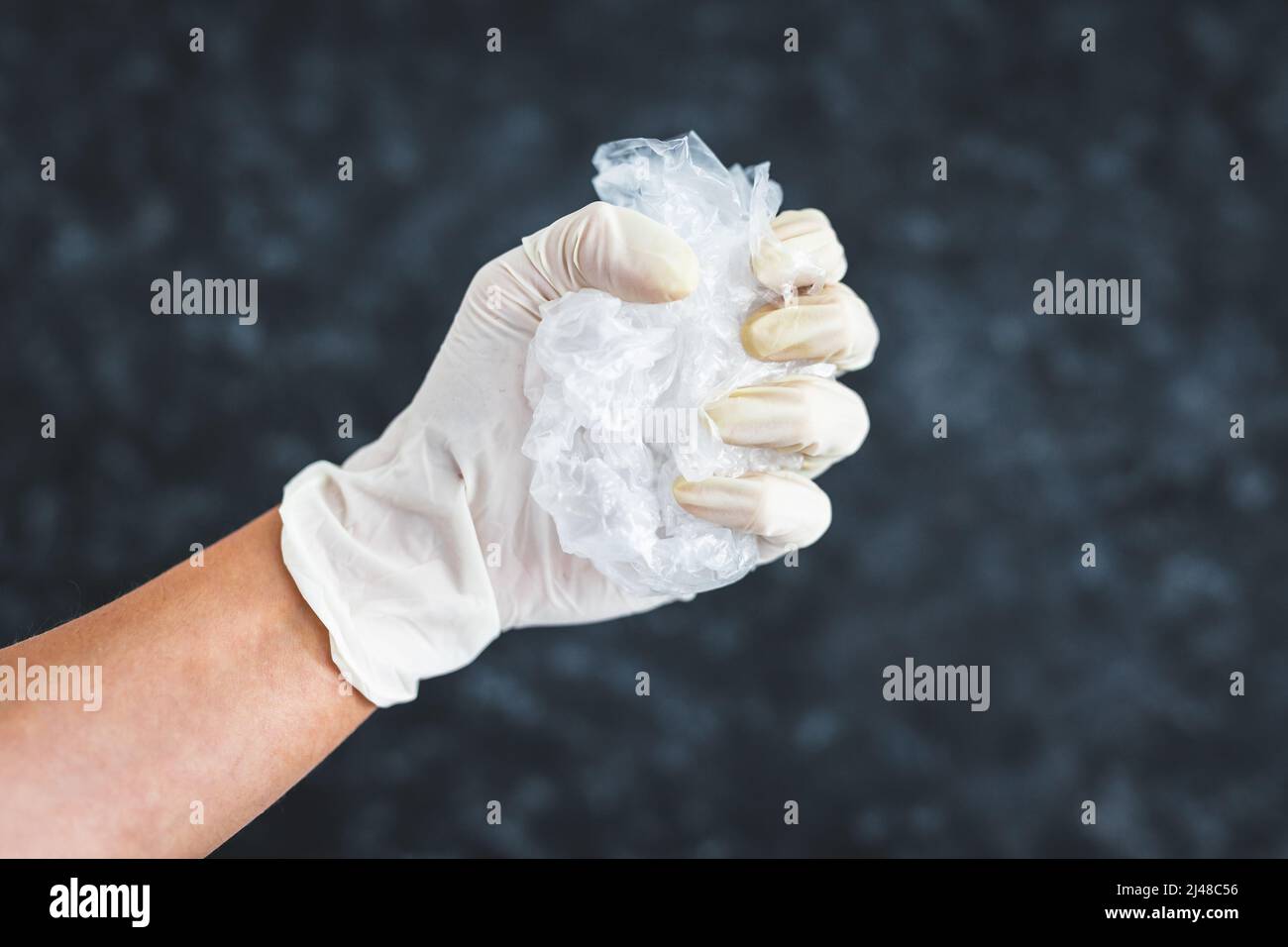 hand with glove picking up single-use plastic bag to be recycled ...