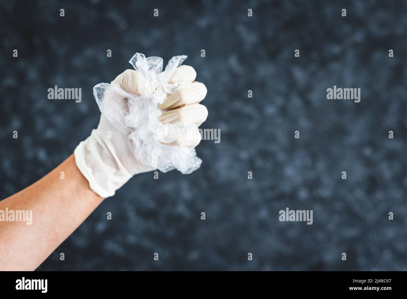 hand with glove picking up single-use plastic bag to be recycled ...
