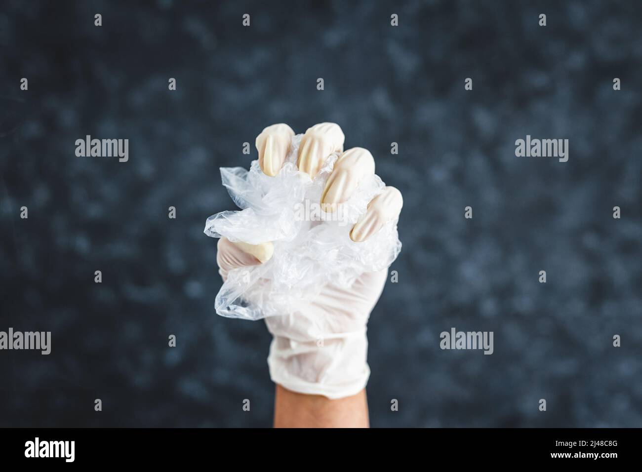 hand with glove picking up single-use plastic bag to be recycled ...