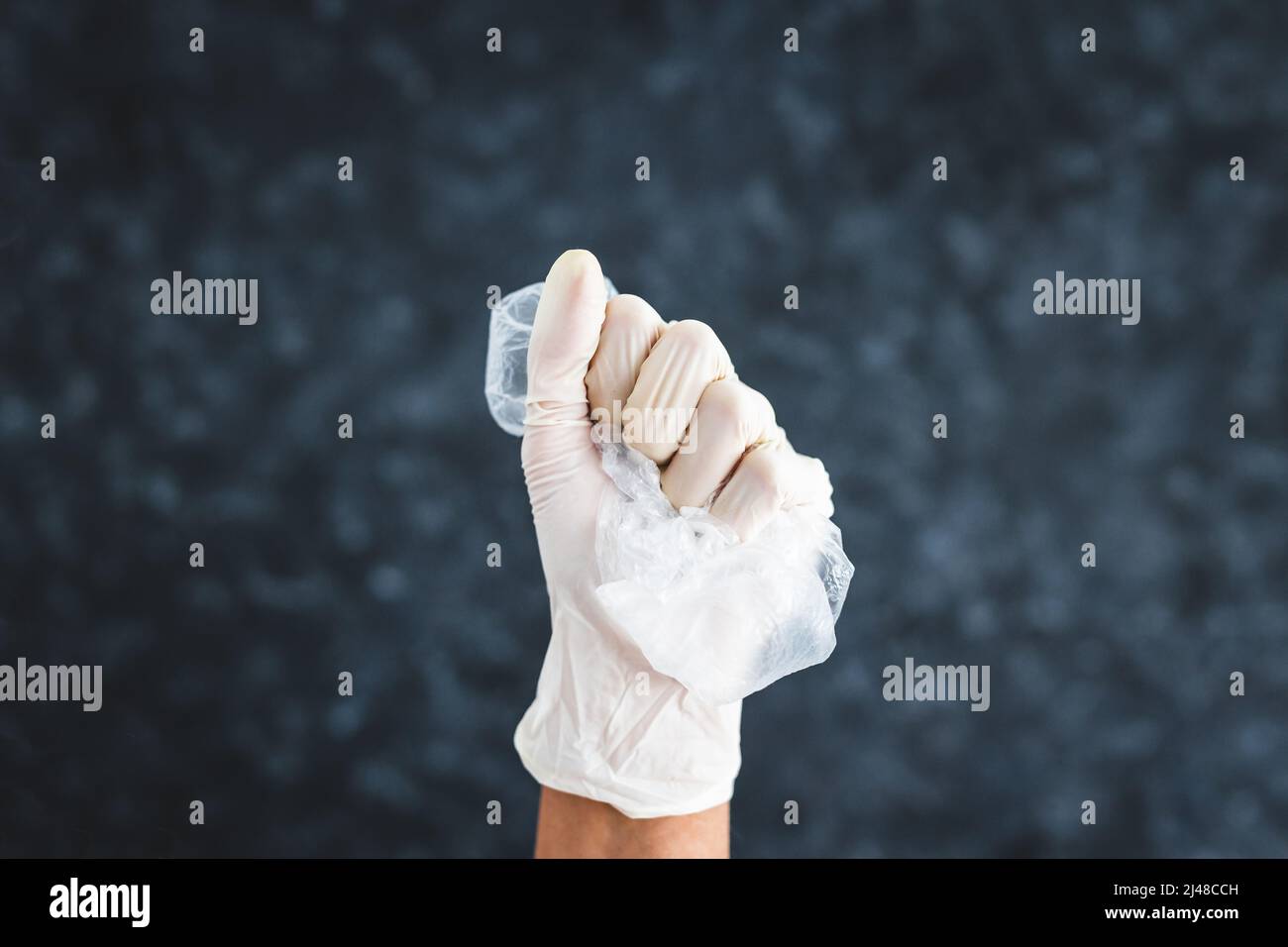 hand with glove picking up single-use plastic bag to be recycled ...