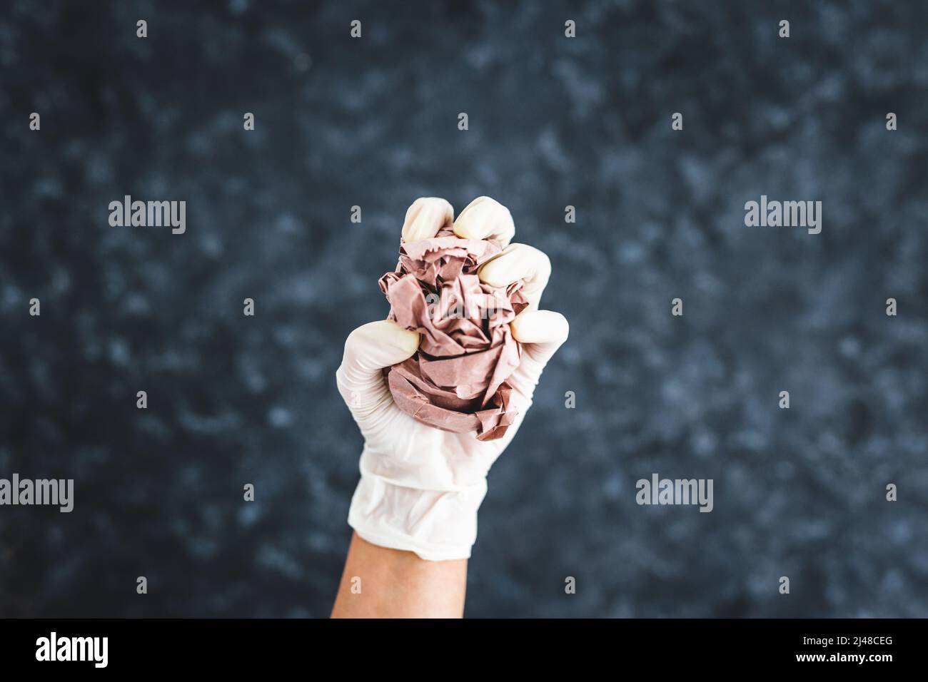 hand with glove picking up single-use plastic bag to be recycled ...