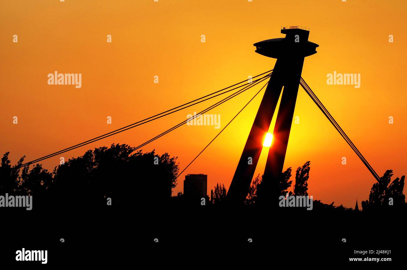 Sunshine and colorful sunrise through silhouette of SNP bridge in city ...