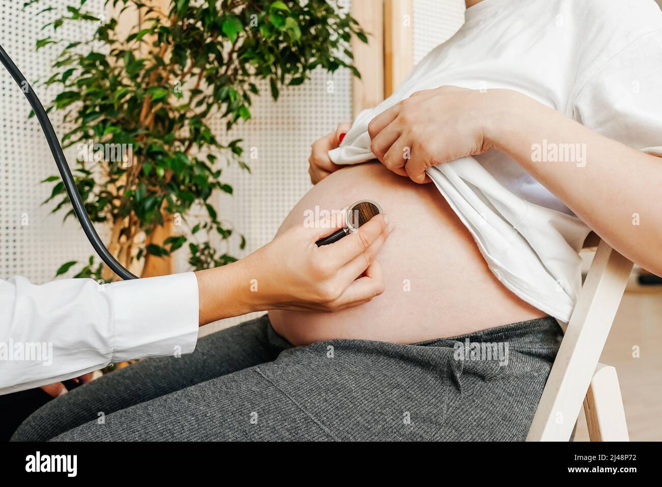 Pregnant woman at the doctor's appointment. Doctor listens to the belly ...