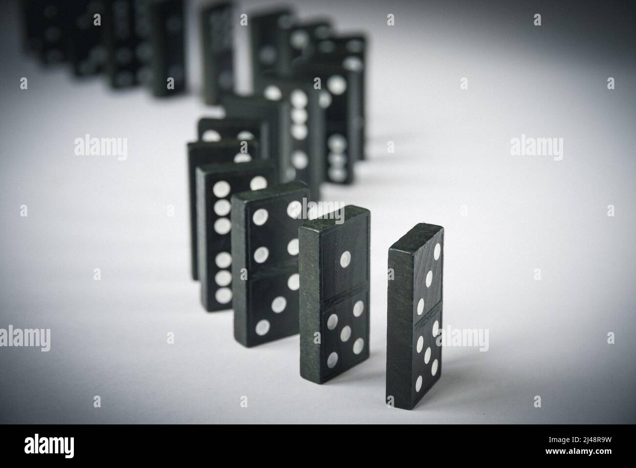 Black dominoes chain on a white table background. Domino effect concept ...