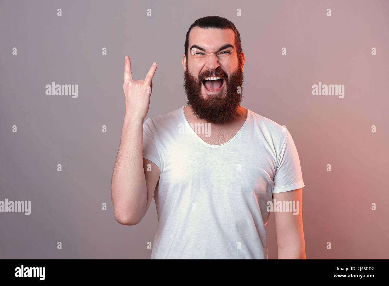 Ecstatic bearded man si showing rock gesture while screaming at the ...