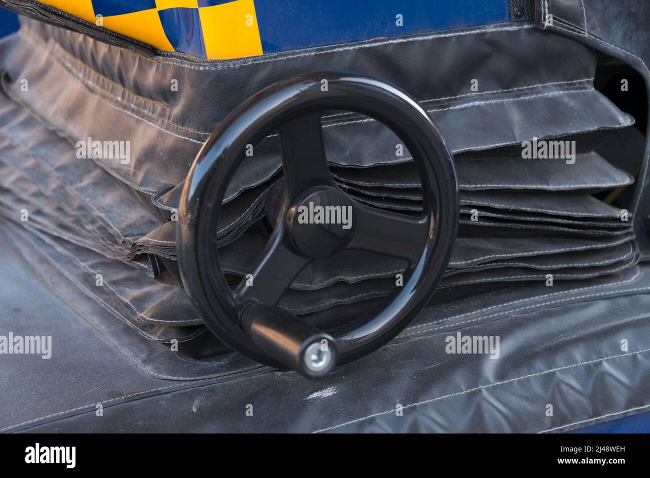 Close up of black rotating wheel with hand crank and a folding bag of ...