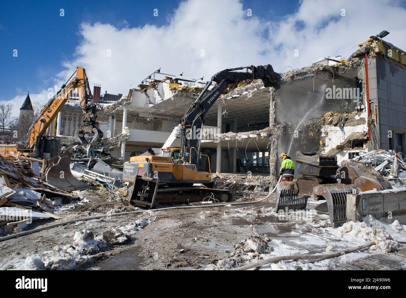 Worker spraying water over a demolition site to prevent dust ...