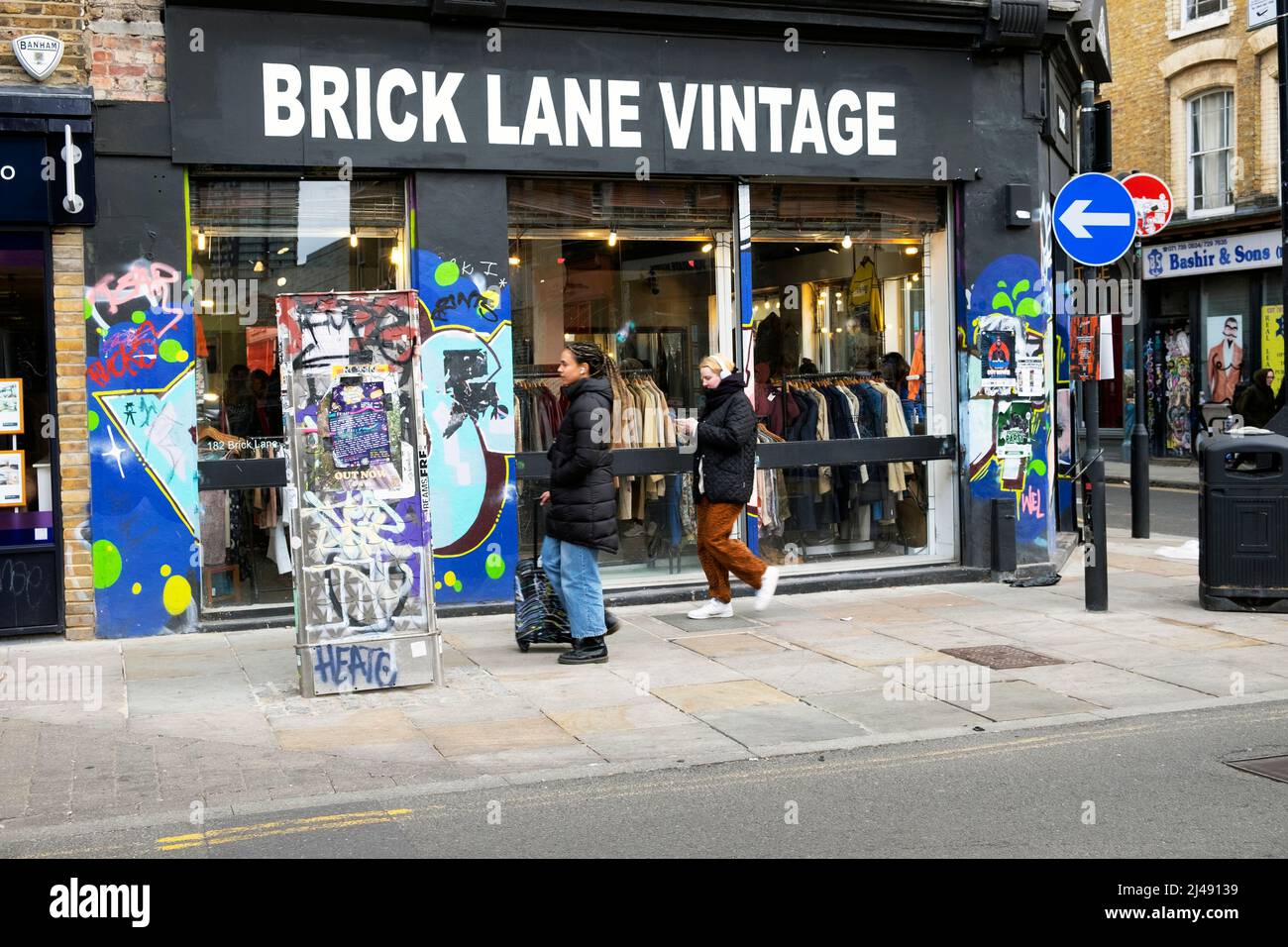 Young women shoppers walking outside past Brick Lane Vintage shop ...