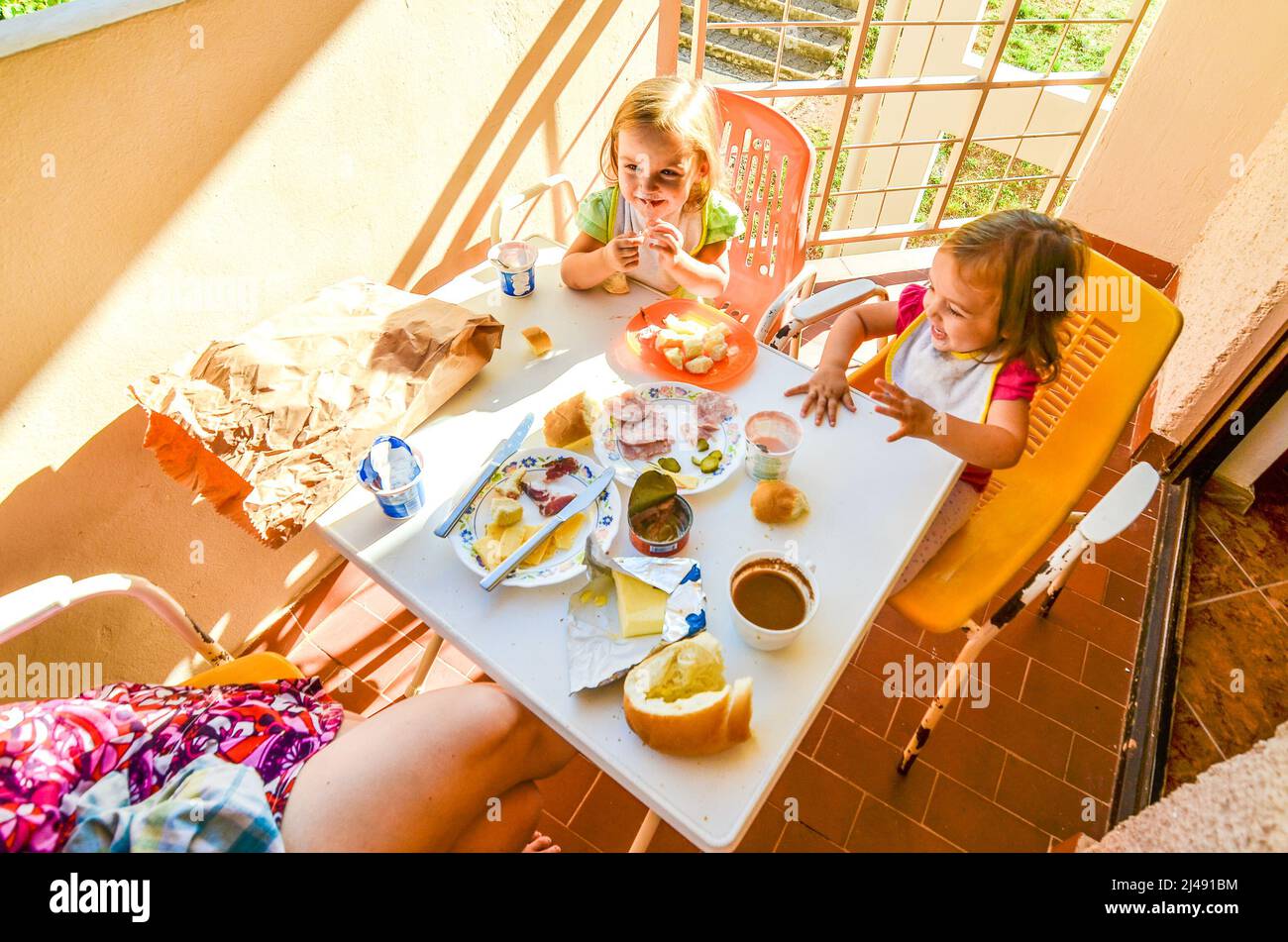 Family eating breakfast on vacation. Mother and children baby twins are ...