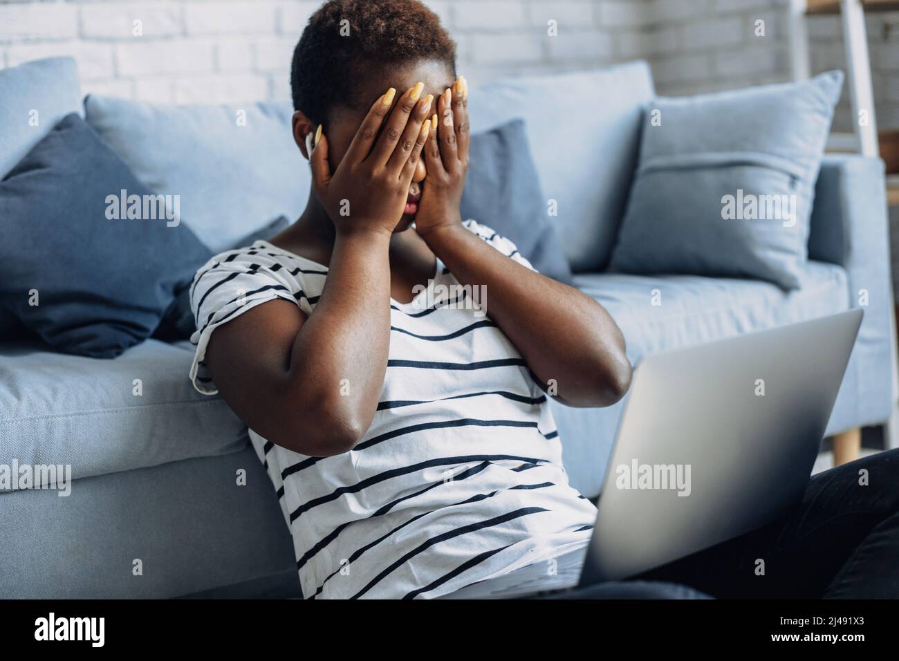 African american woman sitting on the floor using laptop stressed ...