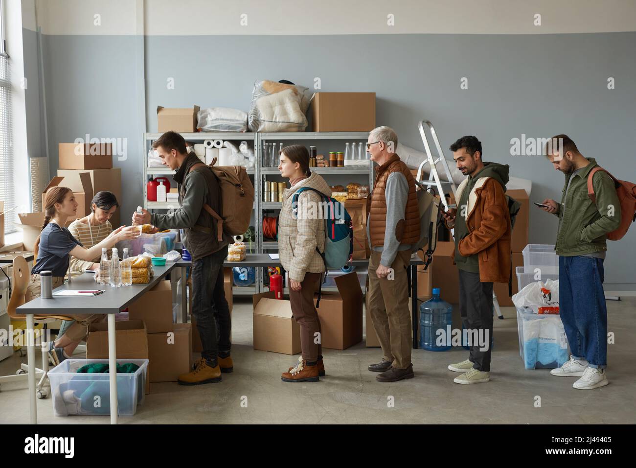 Side view at group of people standing in line at help and donations ...