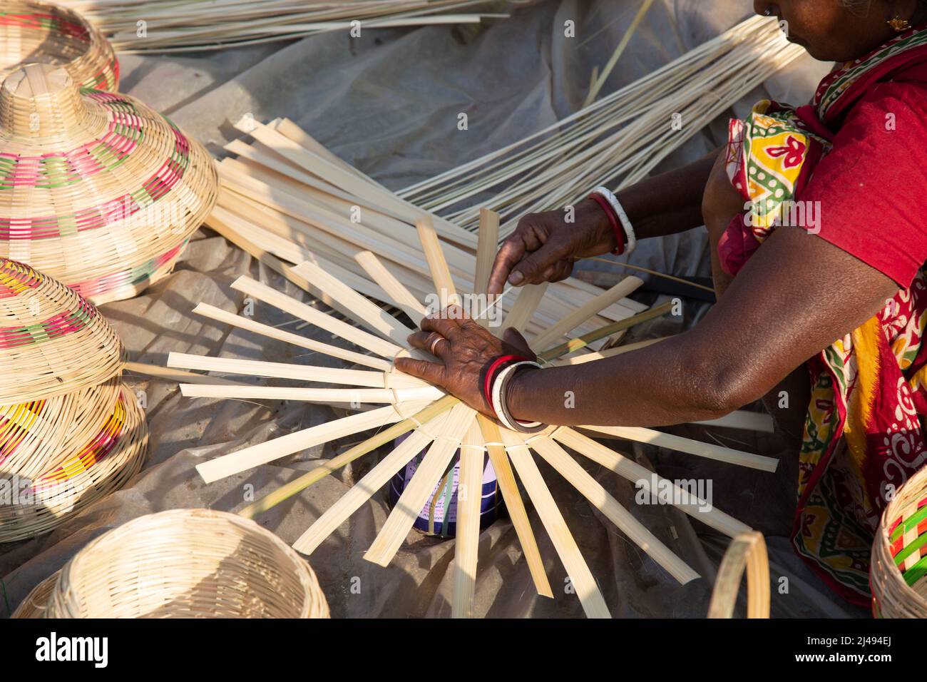 Hands of a working Indian woman in closeup view weaving a basket with ...