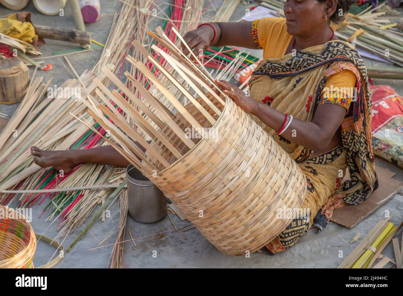 Rural Indian woman weaving a basket with bamboo straws for sale at a ...