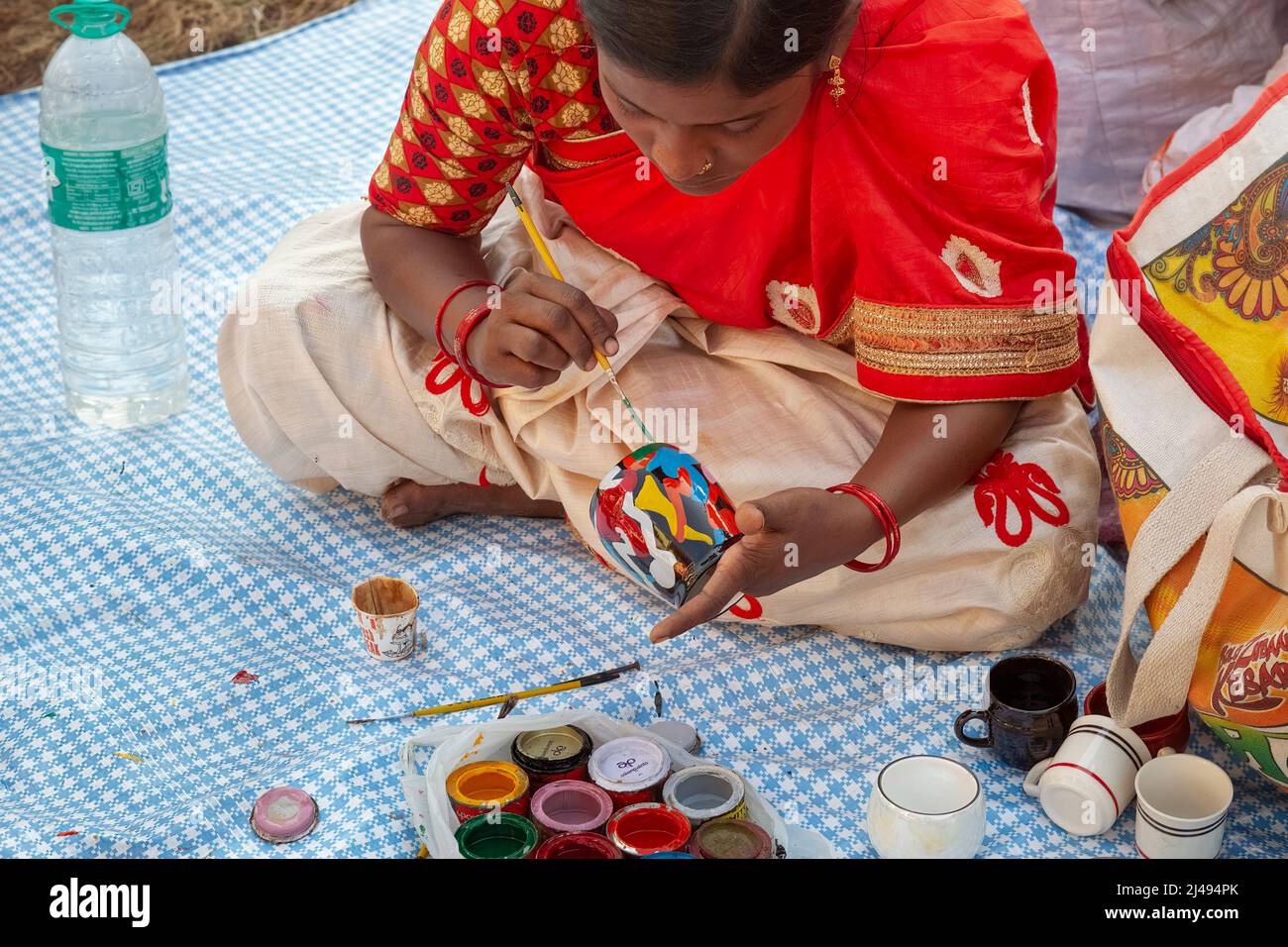 Rural Indian woman in traditional costume painting a clay vase for sale ...