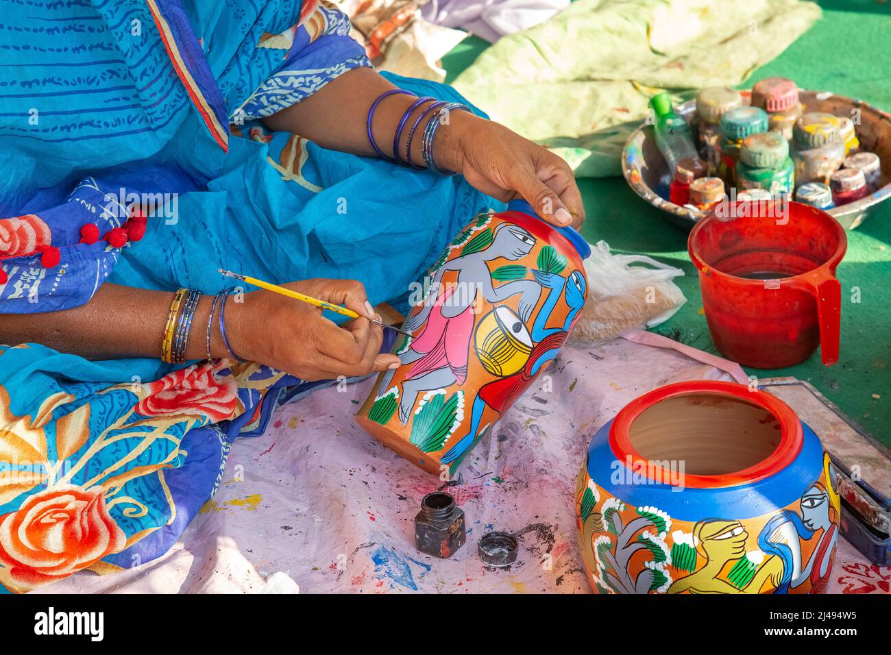 Rural Indian woman in traditional costume painting a clay vase for sale ...