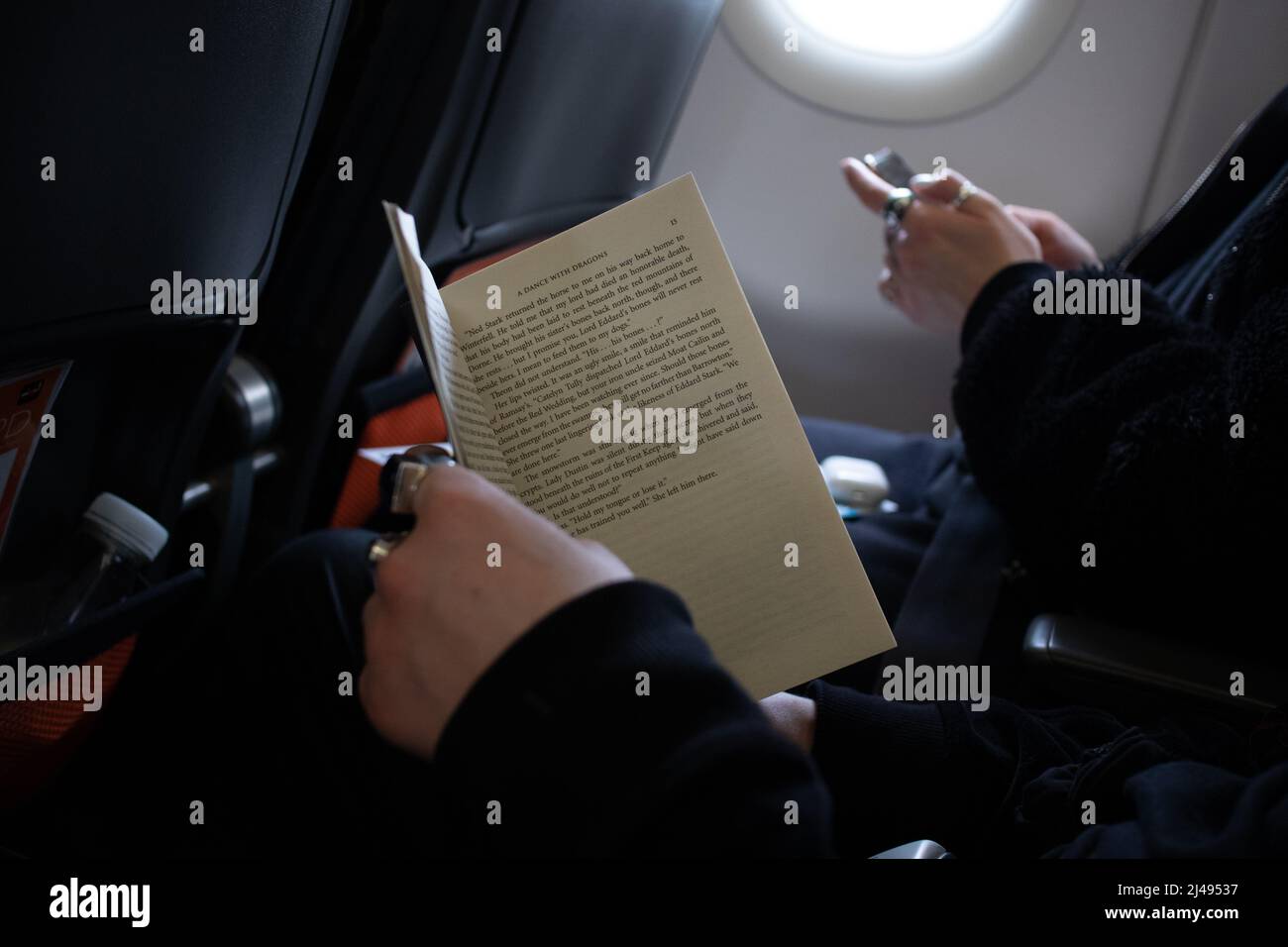 Young adult relaxing by reading a book on a flight Stock Photo - Alamy