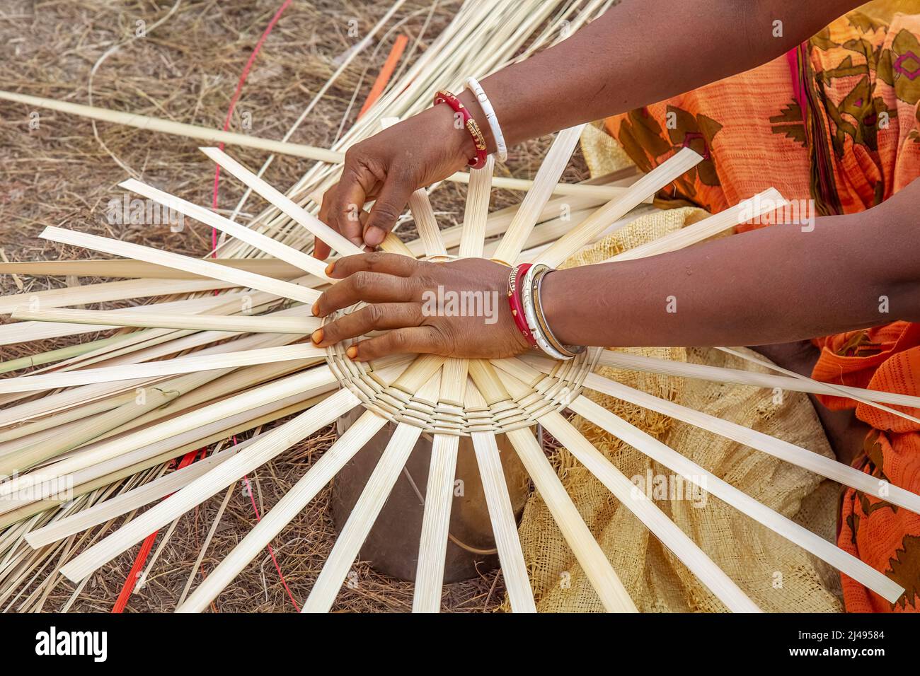 Hands of a working Indian woman in closeup view weaving a basket with ...