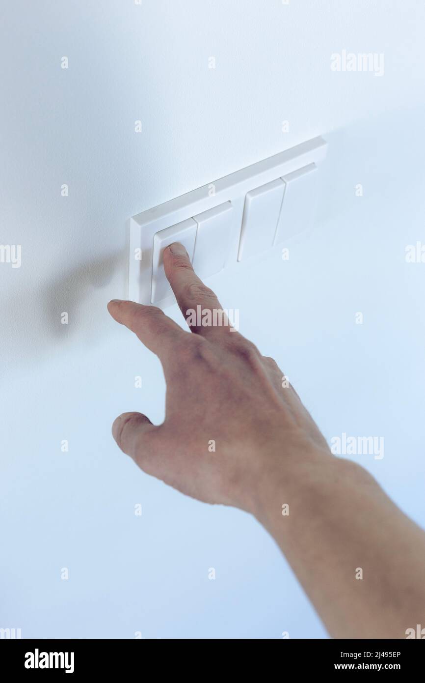 Hand presses a light switch with a finger Stock Photo - Alamy