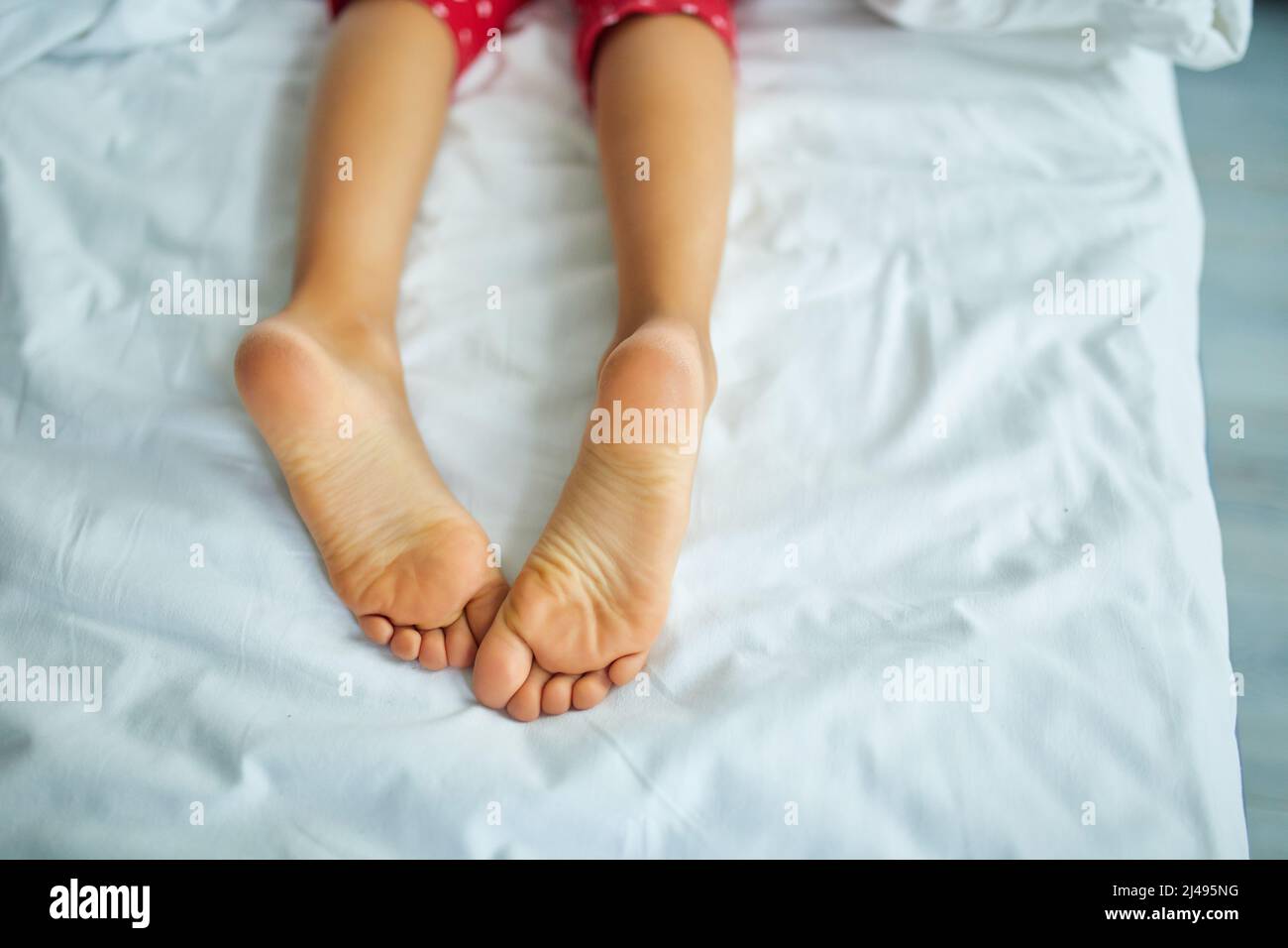 Girl's feet covered with white bed sheet, sleeping in a comfortable bed ...