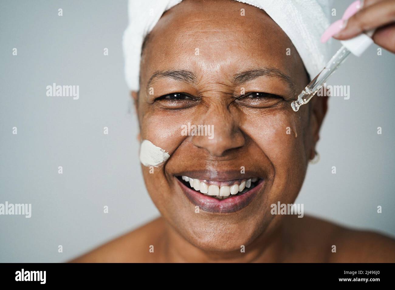 Senior african woman applying hyaluronic drop and skin mask beauty ...