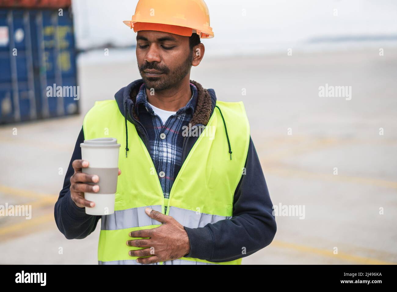 Indian worker drinking coffee with shipping containers on background at ...