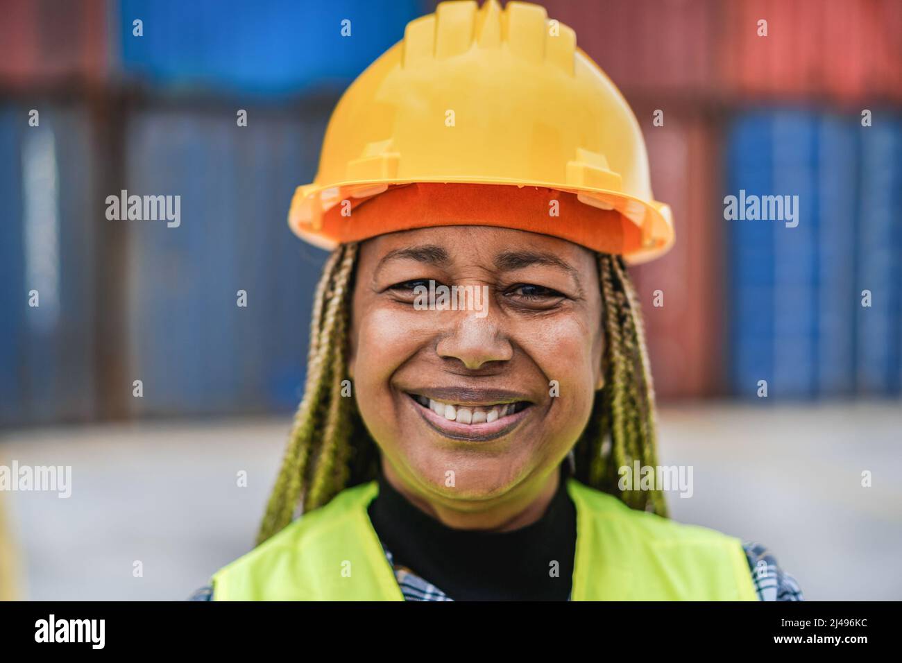 Worker African senior woman smiling on camera with industrial port on ...