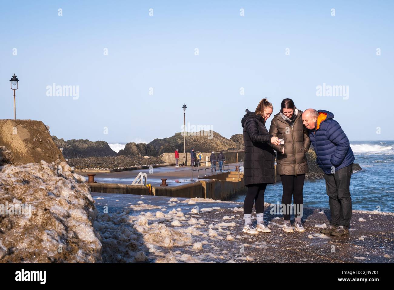 A group of people enjoying the sunny winter weather at Ballintoy ...