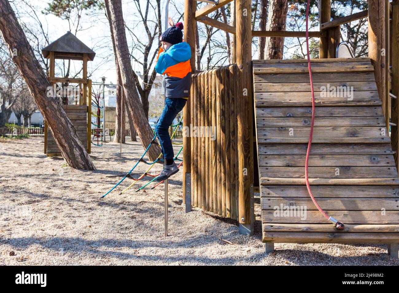 8 year boy child slipping down on a metal tube at playground in cool ...