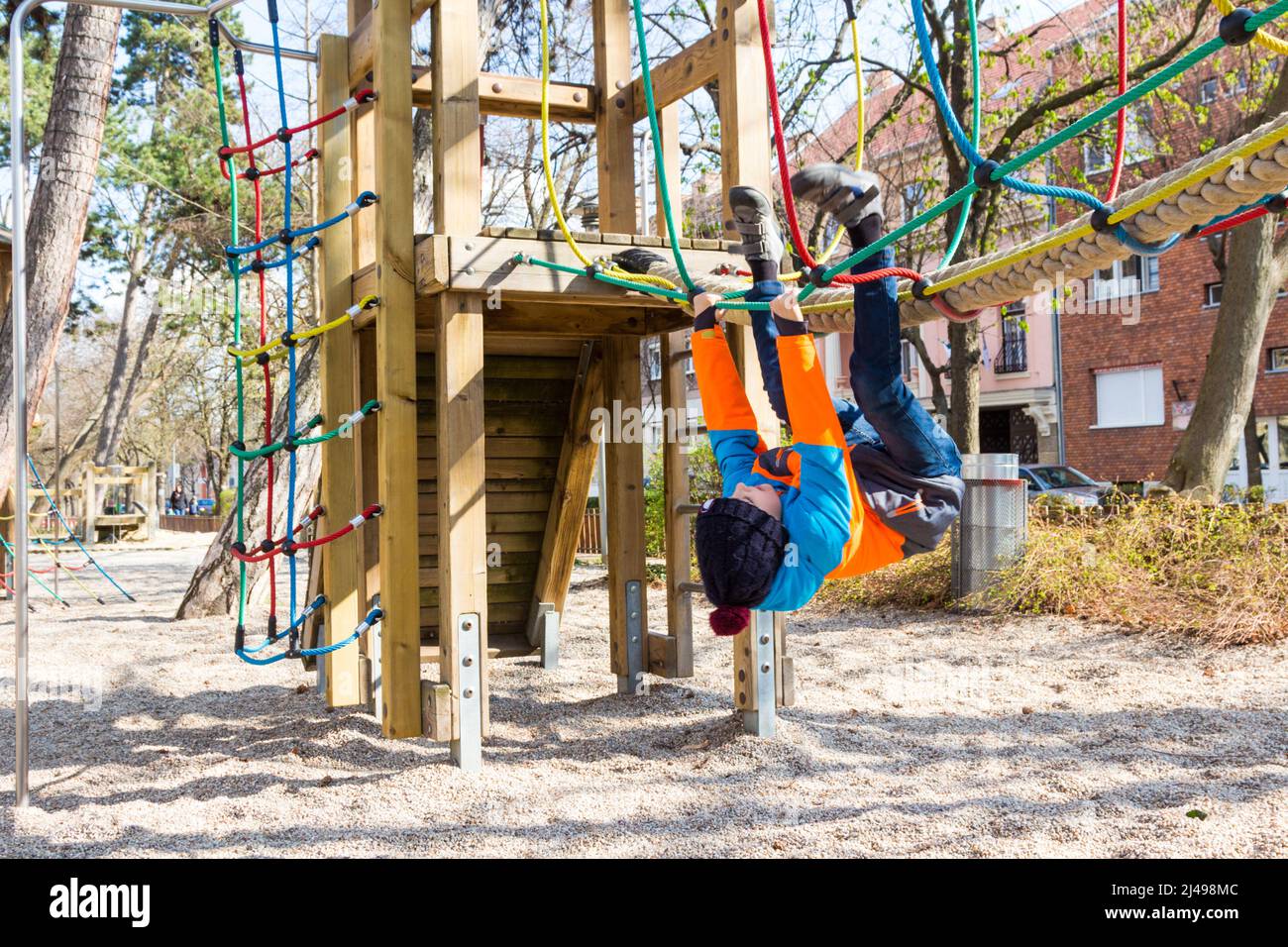 8 year boy child playing on rope bridge at playground in cool weather ...