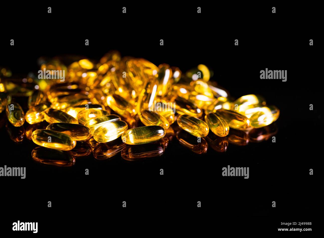 Macro Close up of Omega 3 gel capsule on a reflective black background ...