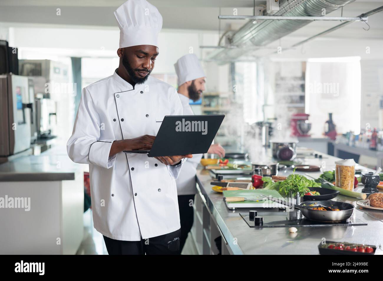 African american head chef with laptop searching for dish recipes on ...