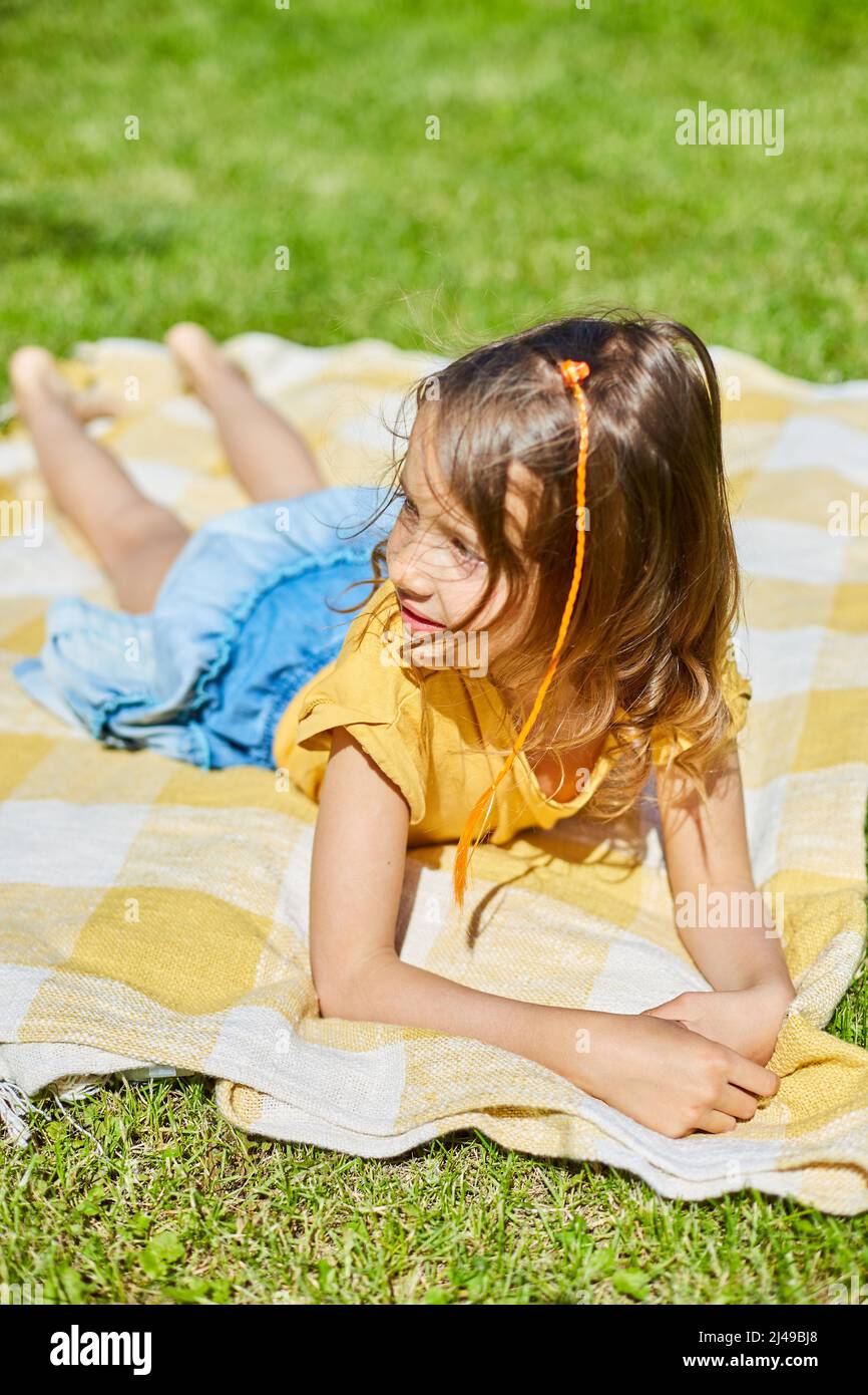 Child lying on the blanket, on the grass in the sun day, little girl ...