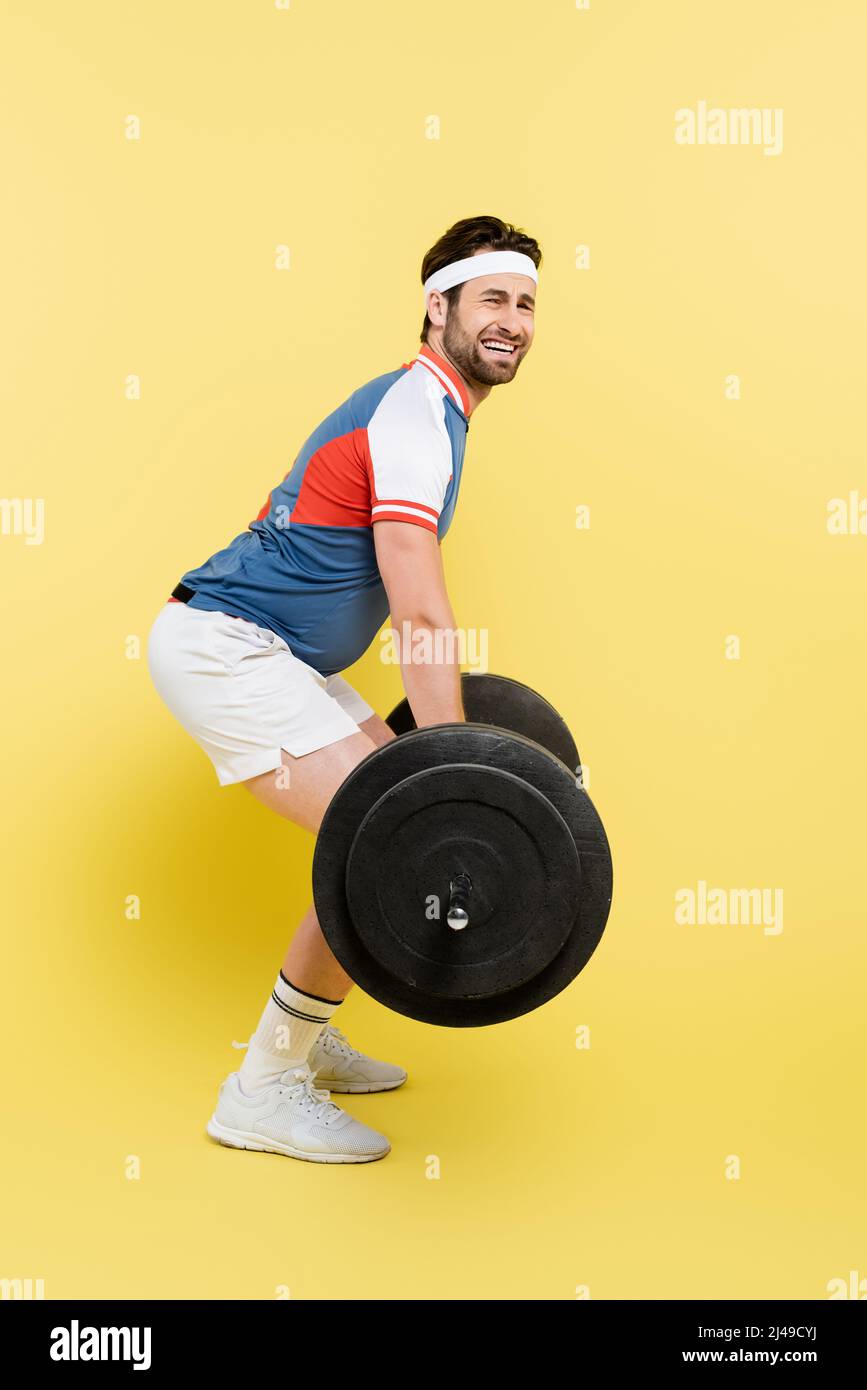 Full length of young sportsman suffering while lifting barbell on ...