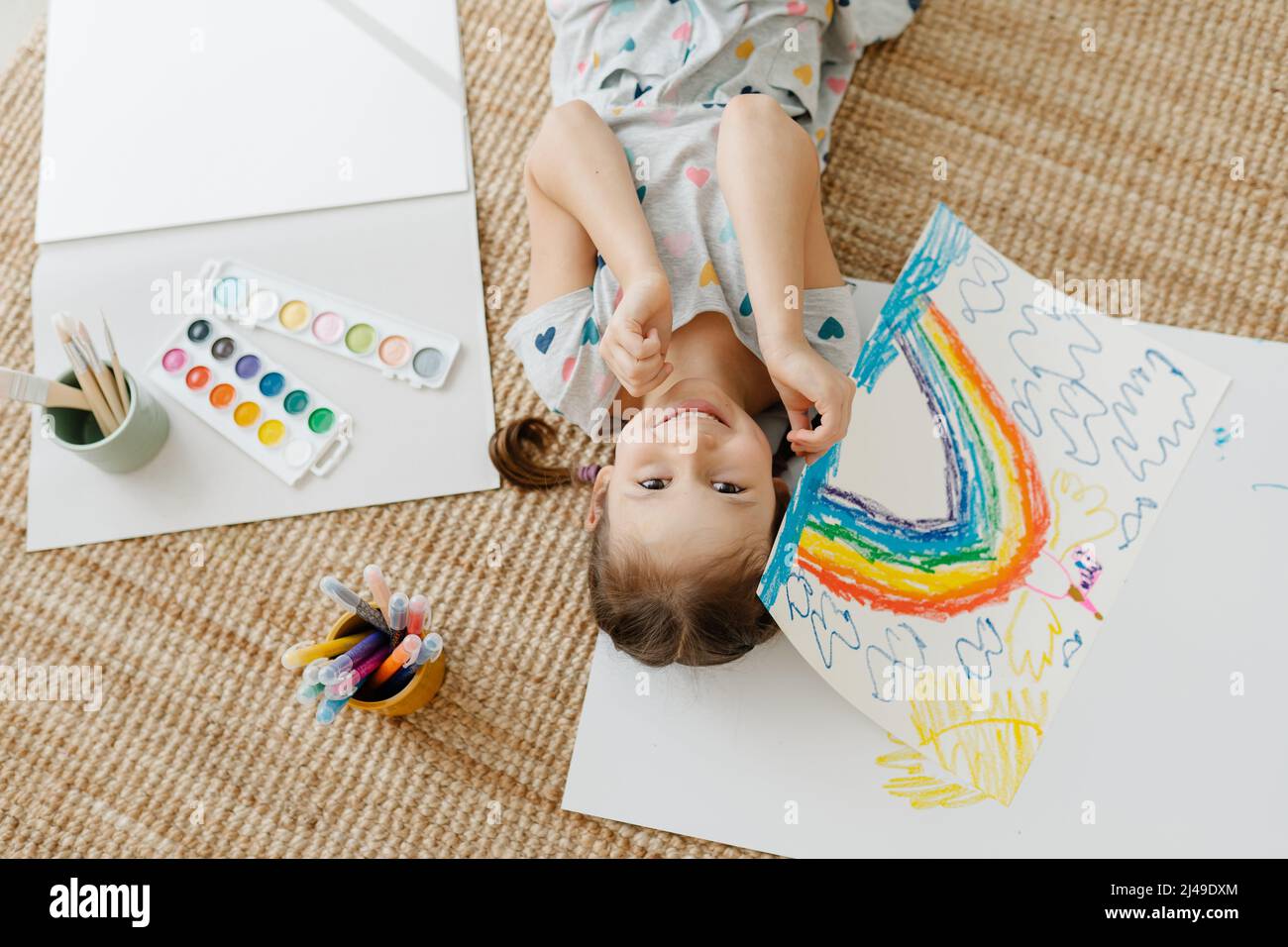 Child lying on floor and hold her draw with rainbow Stock Photo - Alamy