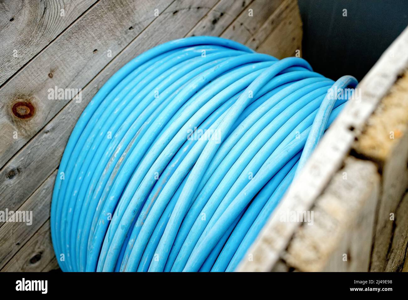 New blue power cable is wound on wooden coil. Background. Cable for ...