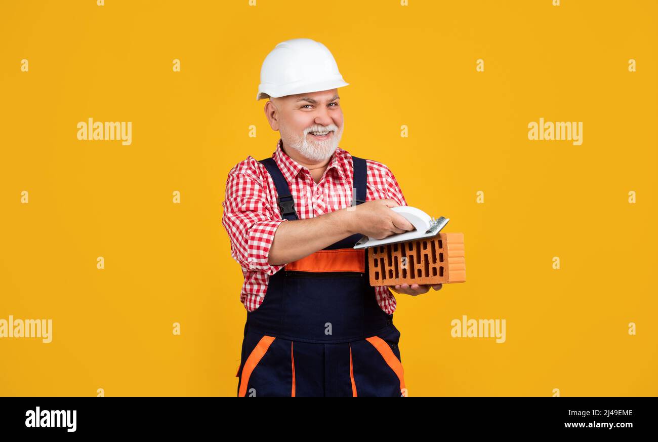happy mature man bricklayer in helmet on yellow background Stock Photo ...