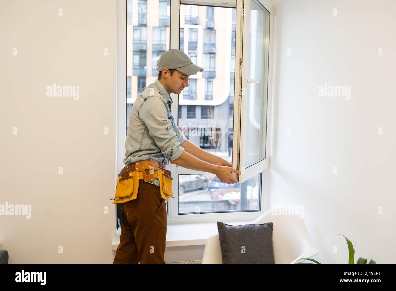 master changing a double-glazed window in a plastic window, side view ...